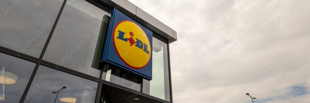 A modern Lidl storefront against a cloudy sky, symbolizing affordable ...