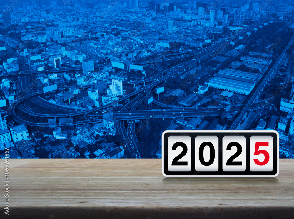 Retro flip clock with 2025 text on wooden table over modern office city ...