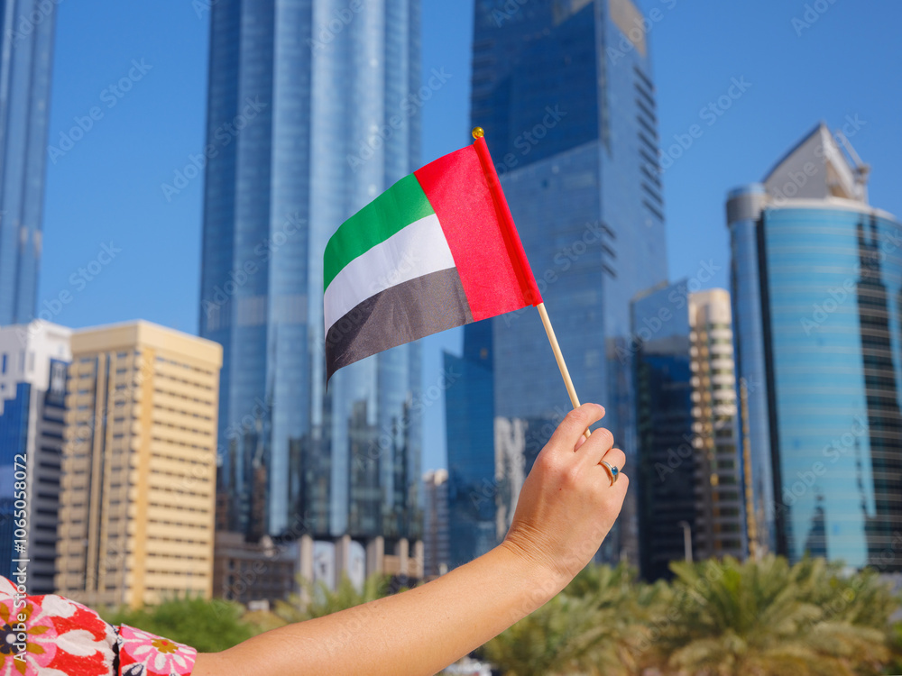 Close up of female hand holding tiny flag of UAE against Abu Dhabi ...