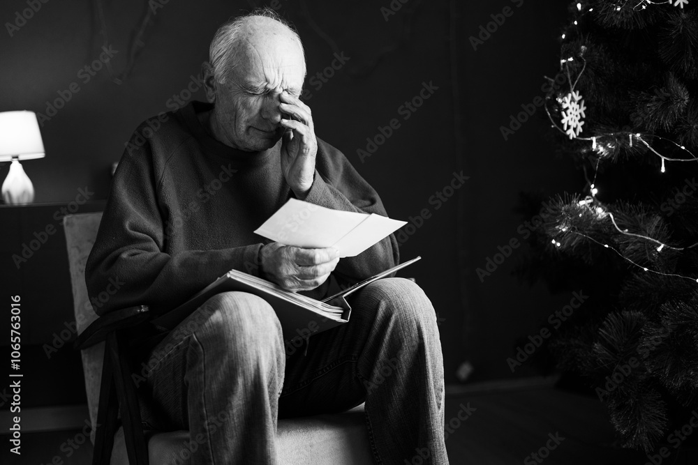 Elderly man crying holding photo from album with retro photographs ...