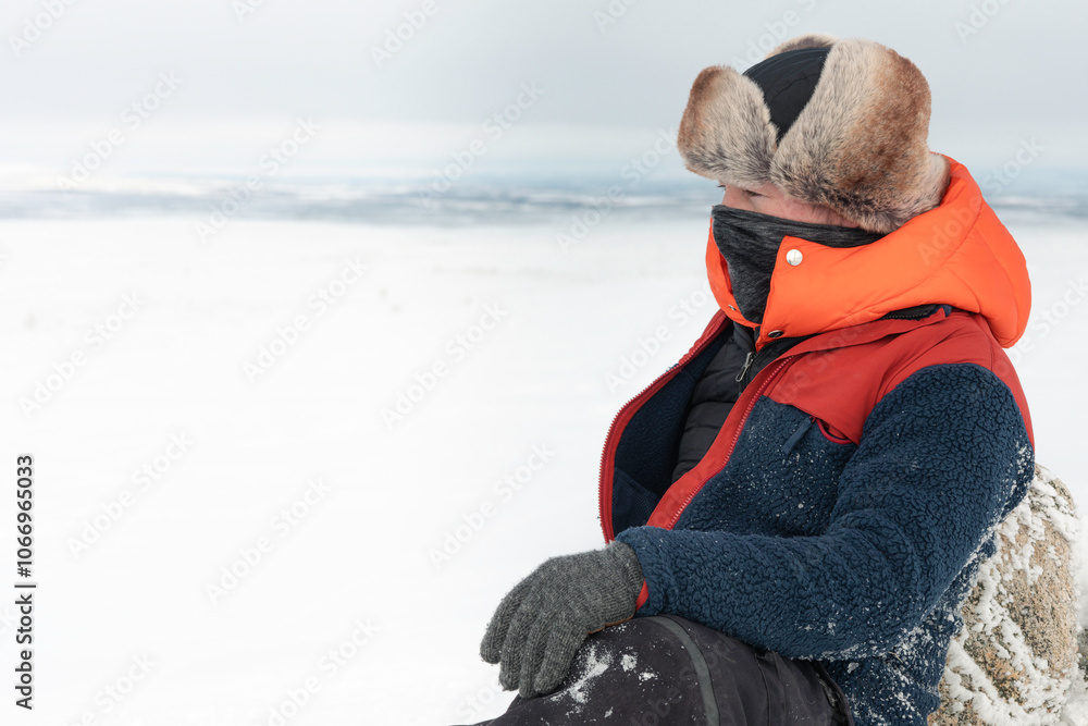 Adult caucasian male musher dressed in full arctic gear sitting on ...