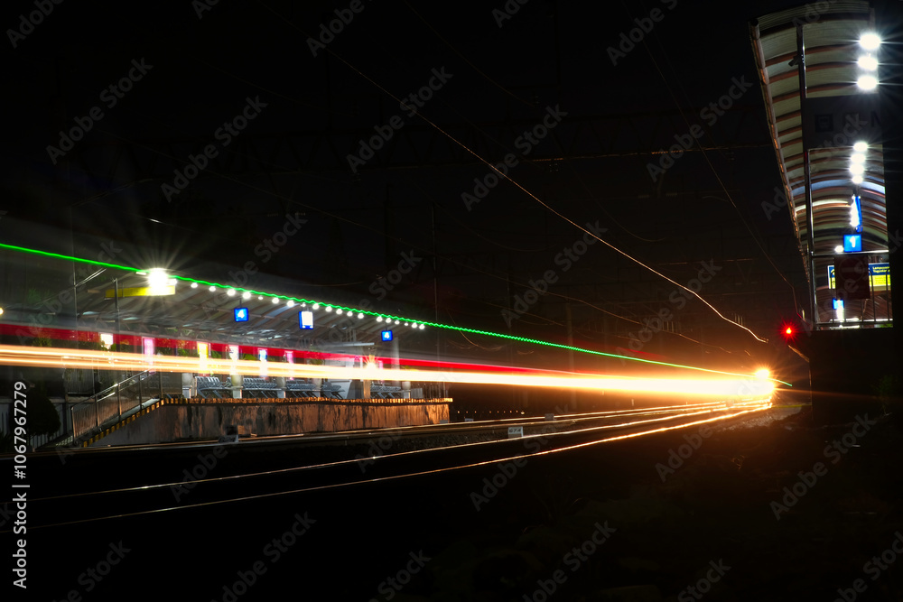 Light trail of fast moving midnight train passing a small station in ...