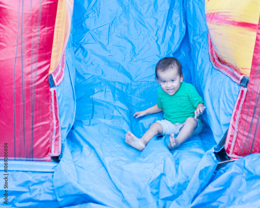 Happy Asian baby boy sliding inflatable bounce house jumping castle ...