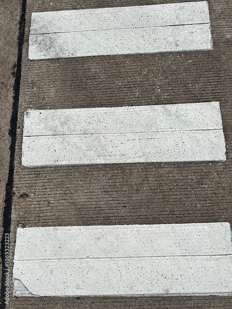 A close-up view of three parallel white stripes on a textured concrete ...