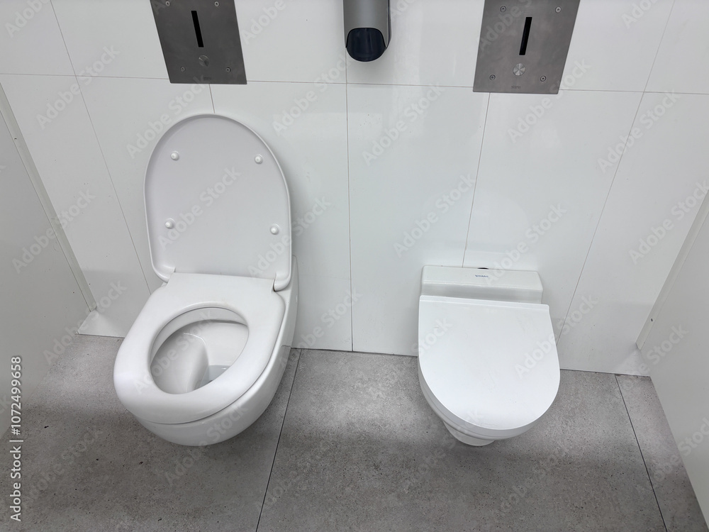 Family restroom stall in a public toilet with two white toilets Stock ...