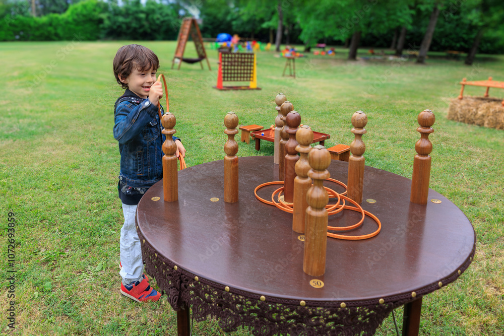 Child playing ring toss game outdoors in park. Recreation and summer ...