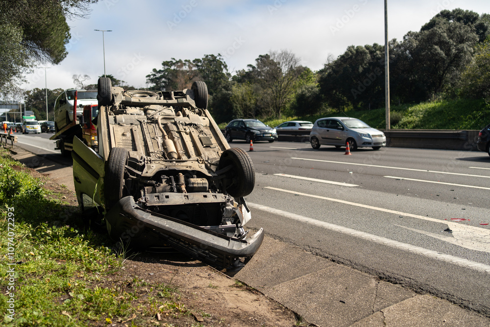 Damaged wrecked car after collision lying upside down on roadside. Busy ...