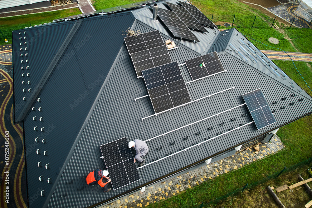 Builders building photovoltaic solar module station on roof of house ...