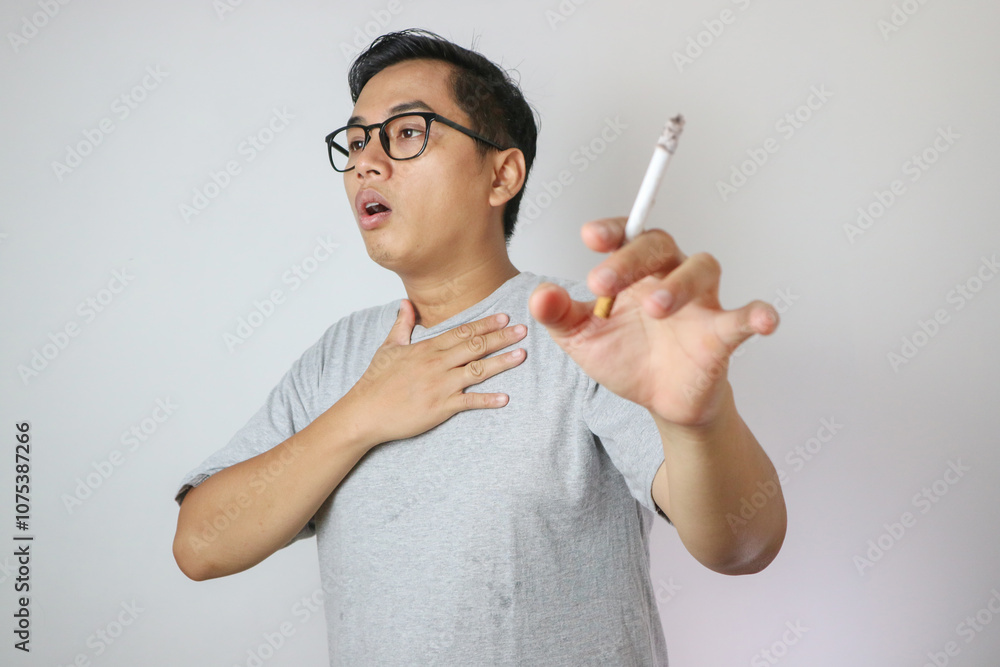 Asian male smoker hold a cigarette,touch his chest pain with hand ...