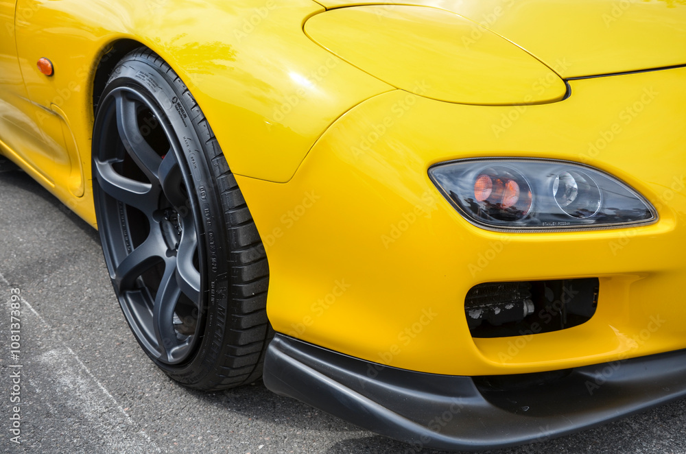 Close-up of the front headlight and wheel of a yellow Mazda RX-7 FD ...