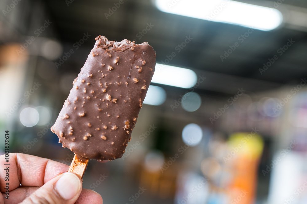 Bitten chocolate popsicle ice cream bar with crushed peanut nuts in ...