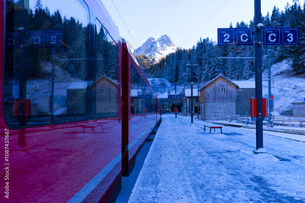 Red train at Swiss railway station of narrow gauge railway RHB named ...