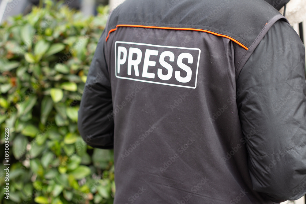 Street photo. Back view. Man or woman in black jacket with inscription ...