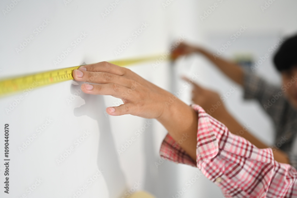 Two people measuring a wall with tape measure for home renovation ...