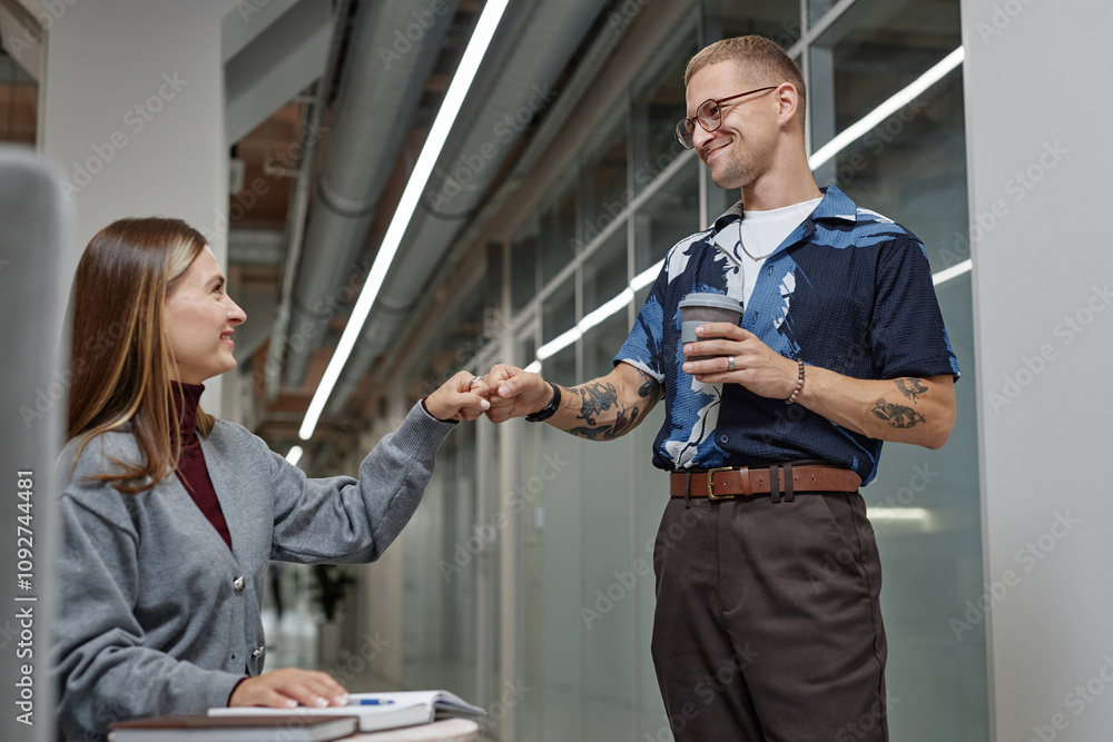 Side view of positive male businessman fist bumping with female ...