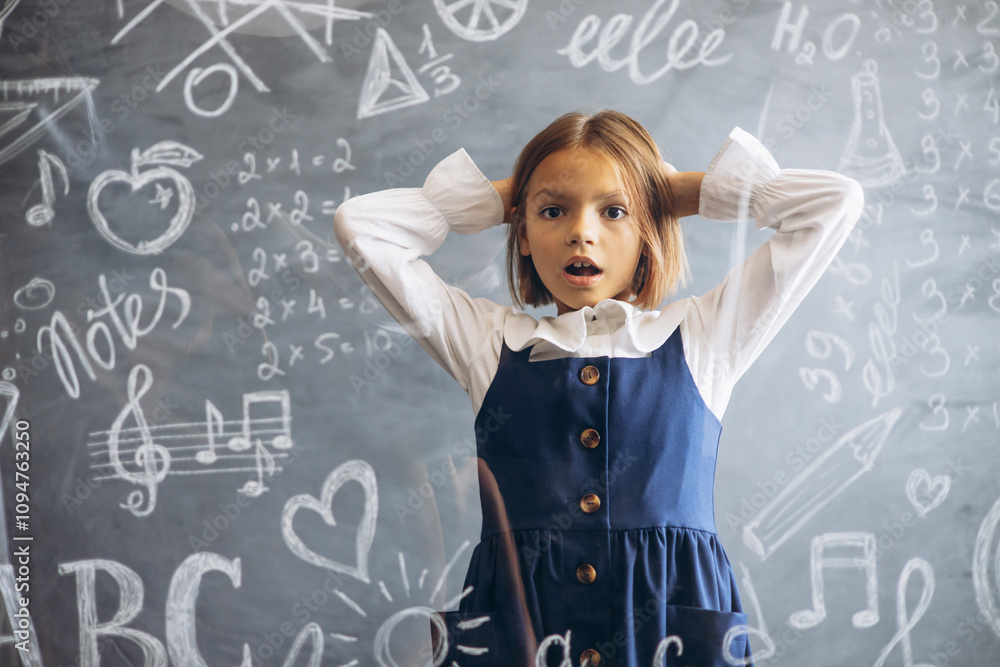 Cute little schoolgirl standing behind the glass board signed with math ...