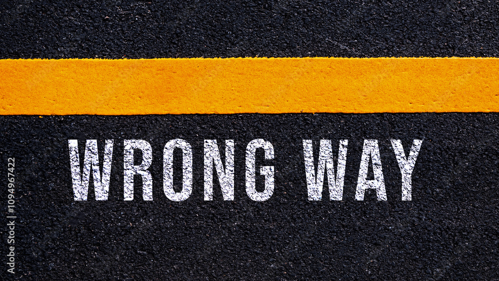 Wrong way, wrong way text written and yellow line on asphalt road ...