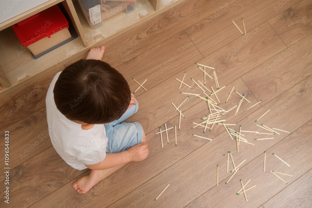 The child is carelessly lighting matches indoors, which could lead to ...