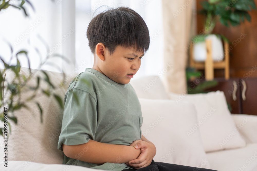 Portrait of sick unhappy little child asian boy touching belly stomach ...
