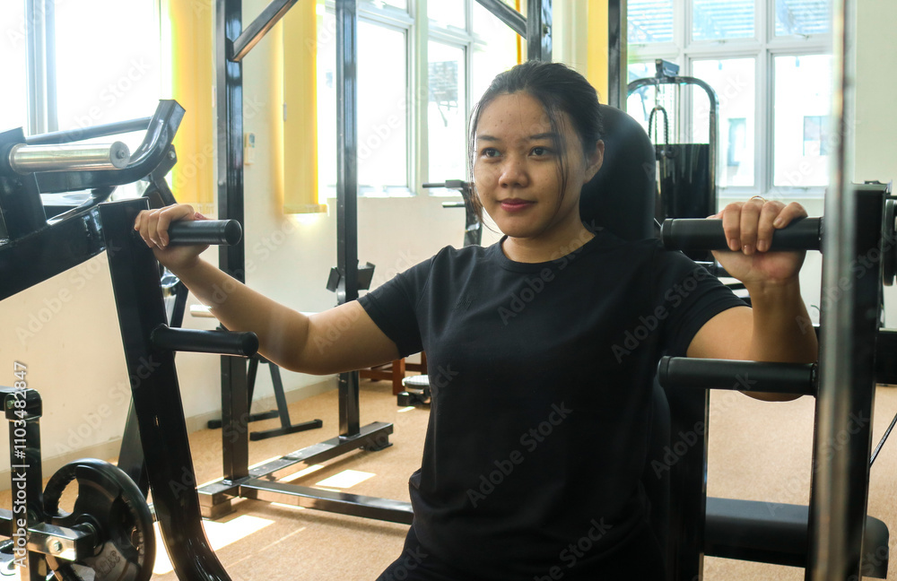 Sporty woman exercising on multi station in gym for arm and shoulder ...