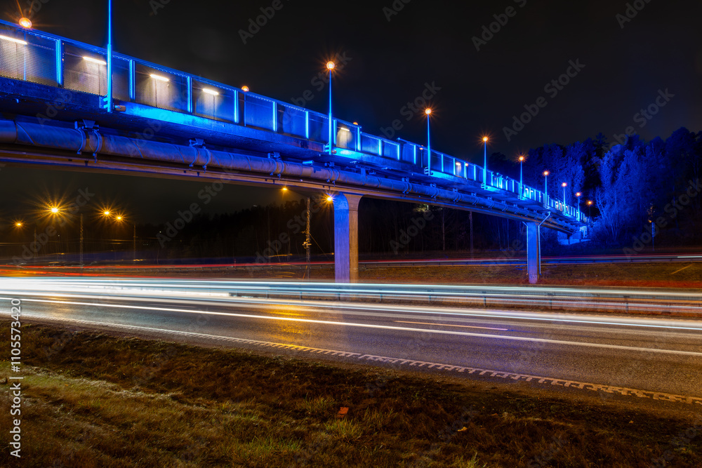 Stockholm, Sweden A blue-lit pedestrian bridge over the E4 Highway and ...