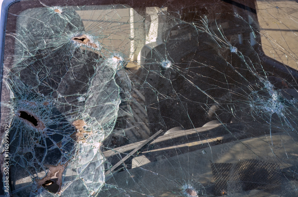 Close-up view of a shattered car windshield showing multiple bullet ...