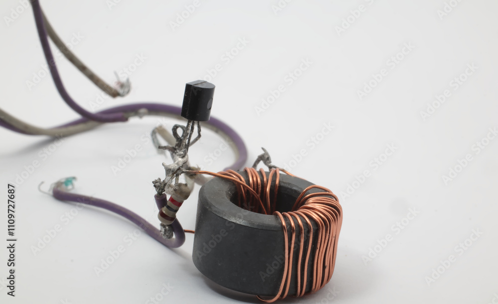 A ferrite core toroid ring with copper windings connected to a resistor ...