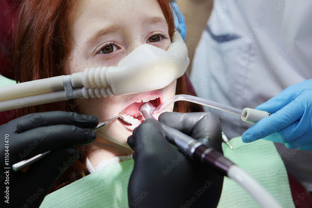 Dental treatment in child with sedation. Little girl is injected with ...