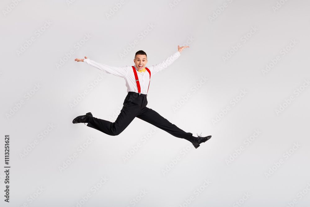 Energetic young man in vintage attire leaping joyfully against a white ...