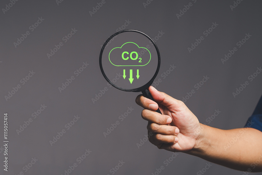 Hand holding magnifying glass with CO2 cloud icon, concept of carbon emissions and reduction ...