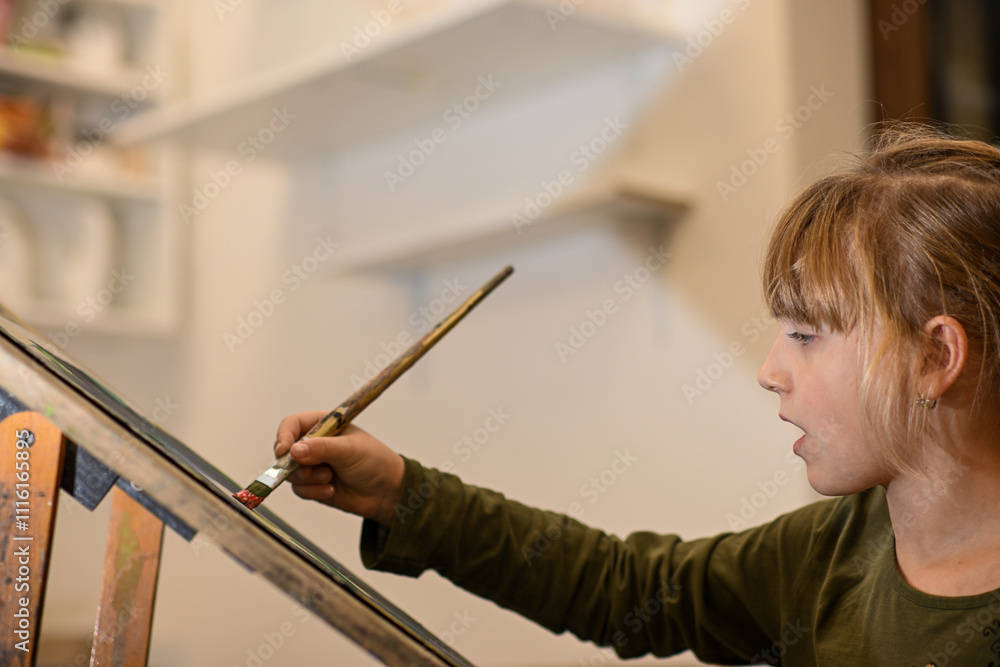 Elementary school student painting abstract art on canvas using ...