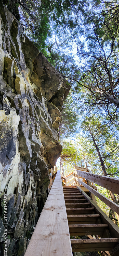 Wooden railing and hiking stairs bolted, attached to the side of a ...