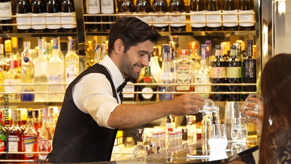 Smiling smart bartender pouring soda or tonic into glass to serve ...