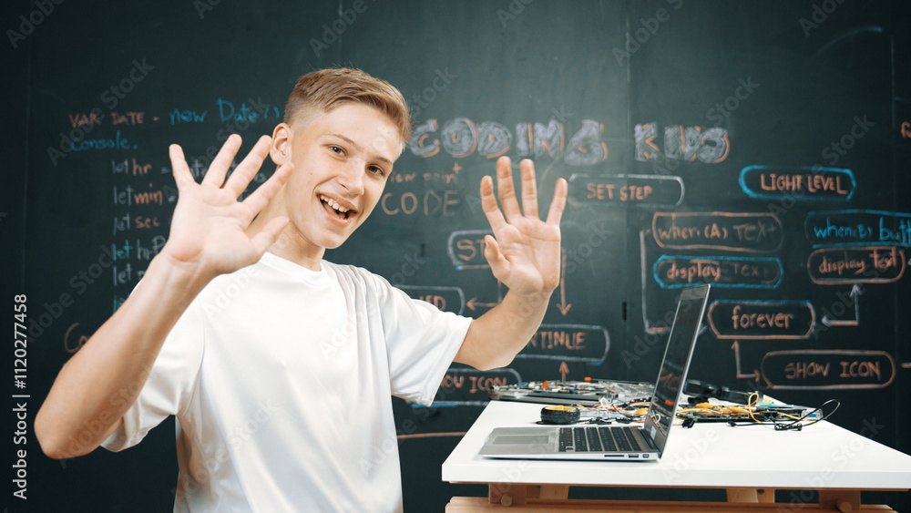 Side view of young boy programing code while looking at camera and ...