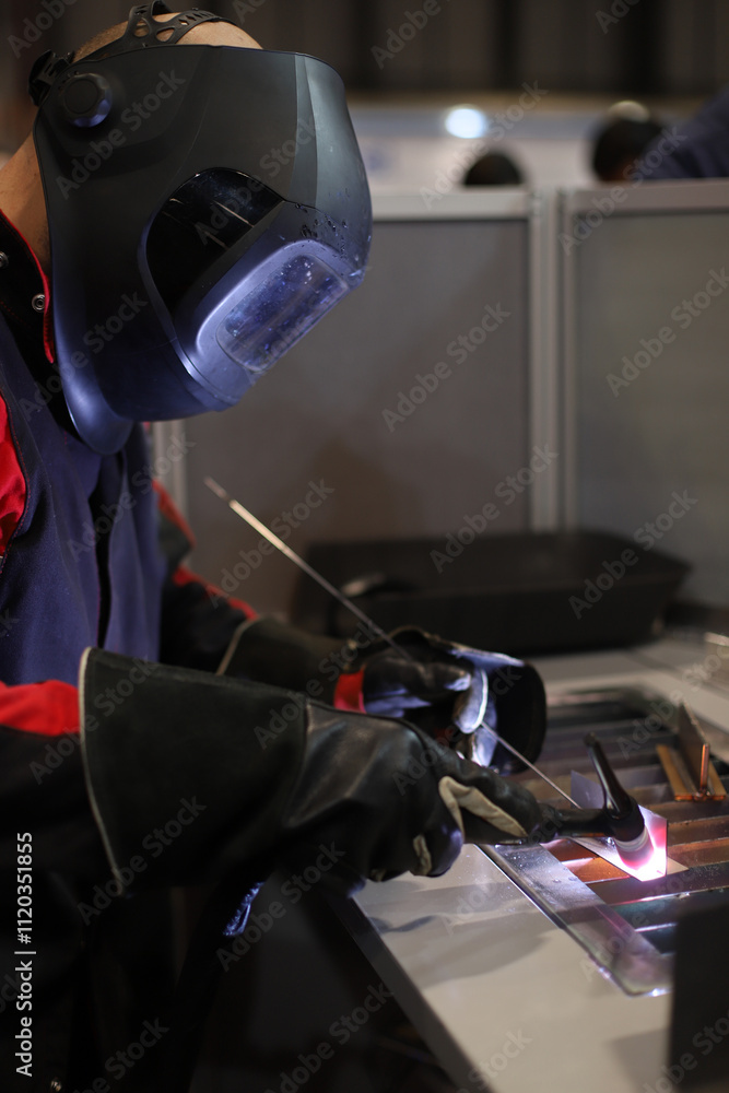 Professional expert welding a piece of metal with an induction welder ...