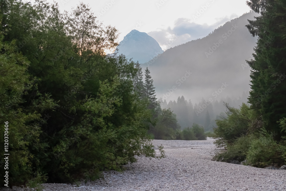 Misty alpine landscape with dried river winding through valley ...