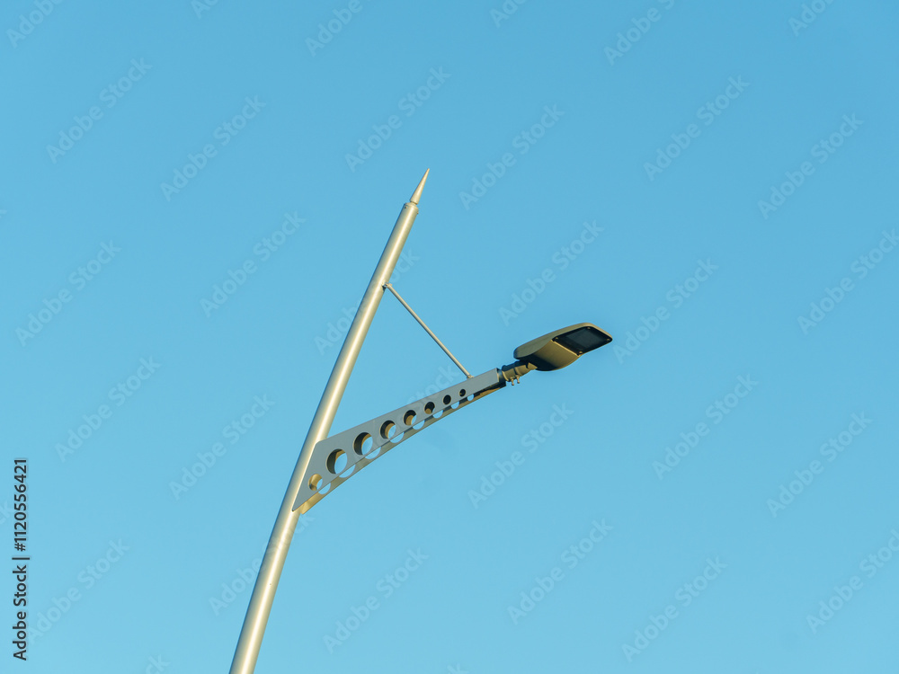 A modern streetlight is prominently displayed against a clear blue sky ...