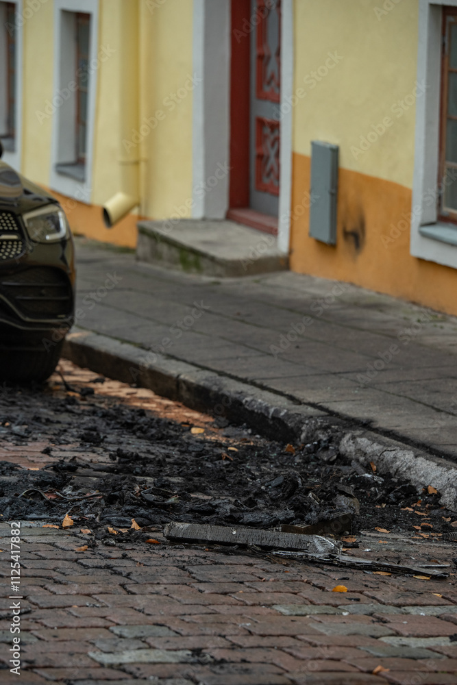 Foto de Stock Charred remains on a cobblestone street where a car has ...
