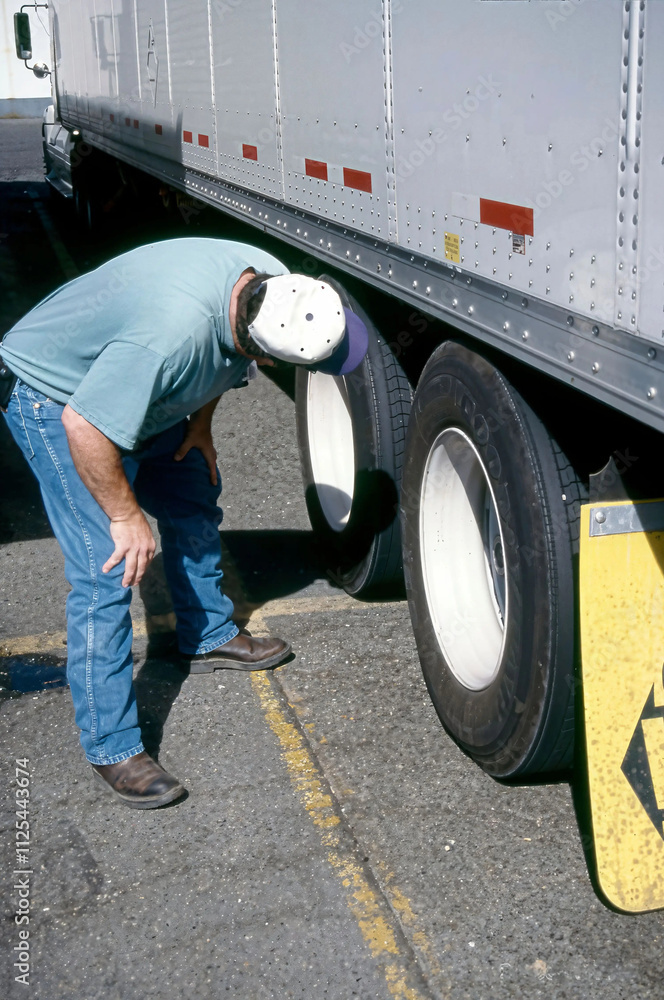 Driver conducts pre or post trip inspection of trailer frame and tires ...