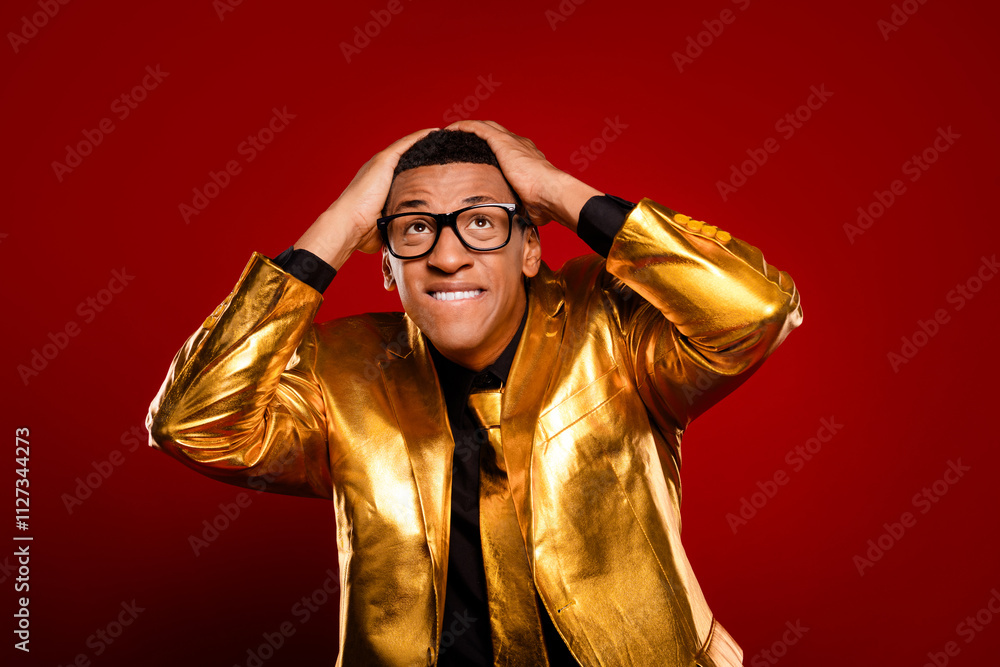 Young man with charismatic expression in a shiny gold jacket on a red ...