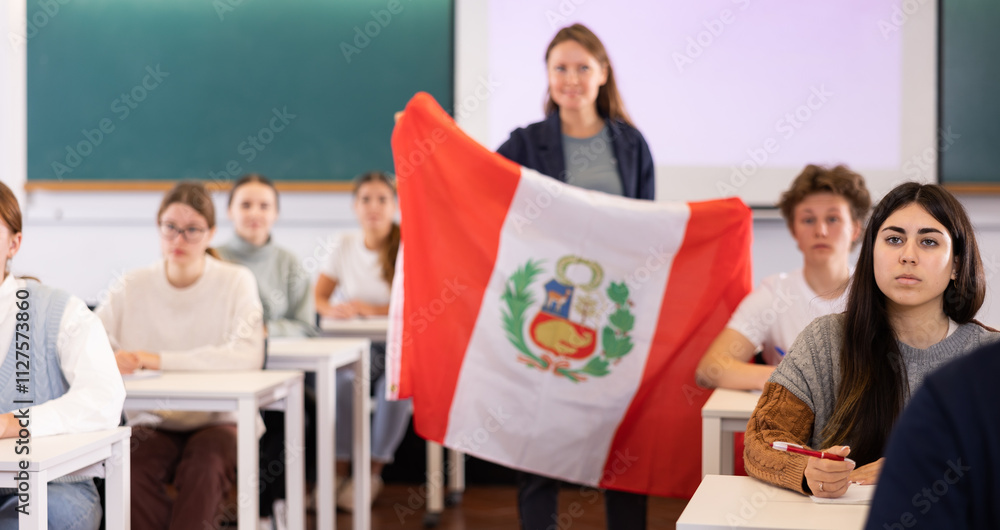 Students study in classroom, teacher stands behind with Peruvian flag ...