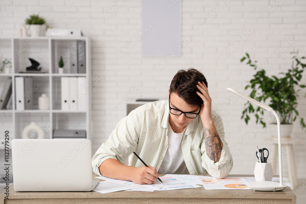 Male economist working with diagrams at table in office Stock Photo ...
