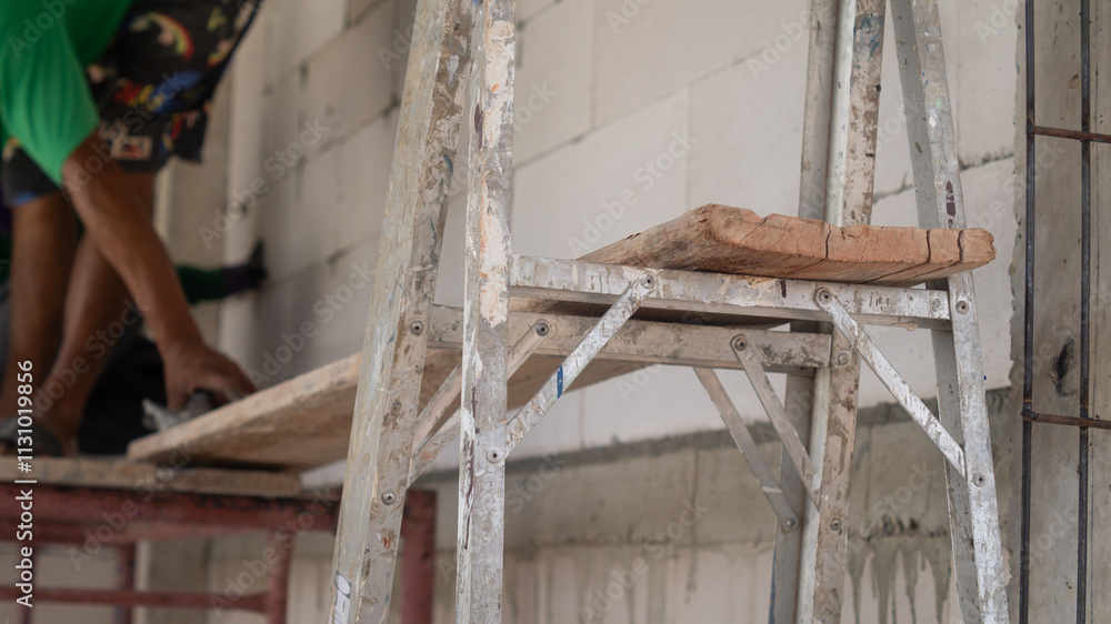 Solid wooden planks are placed over aluminum ladders and construction ...