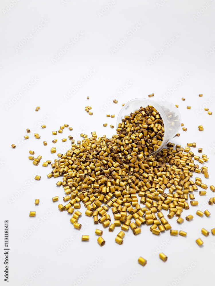 Gold color masterbatch granules spilled from the cup and isolated on ...