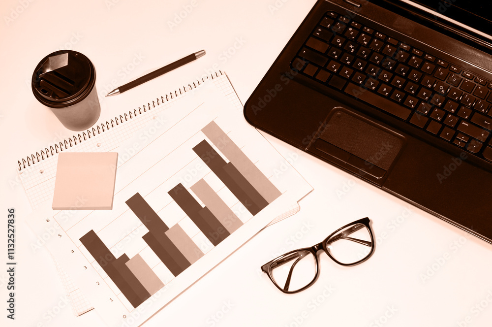 Desktop with laptop, charts, stationery and a glass of coffee in color ...