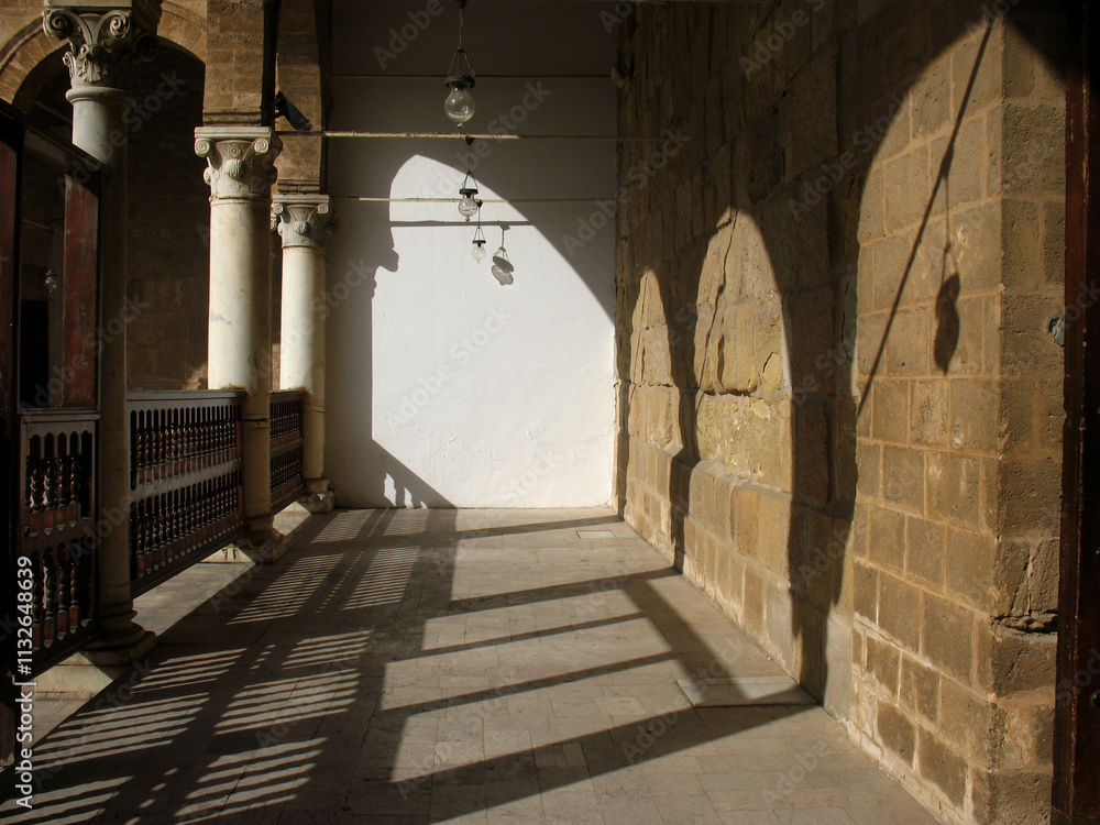 Sunlit corridor with cast shadows from decorative arches and railings ...