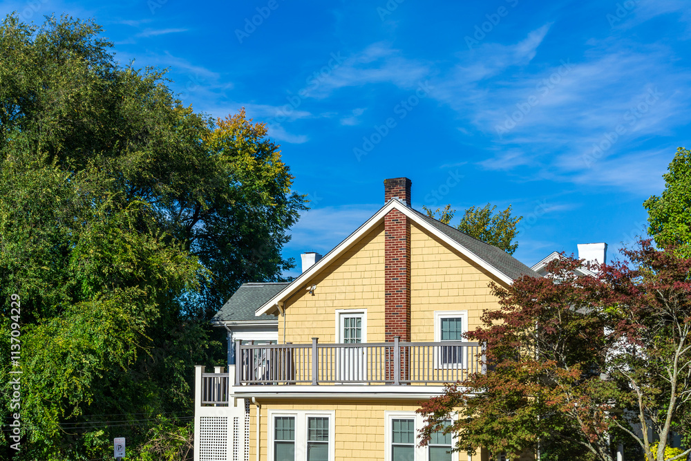 Two-story yellow house with red brick chimney and balcony in Brighton ...
