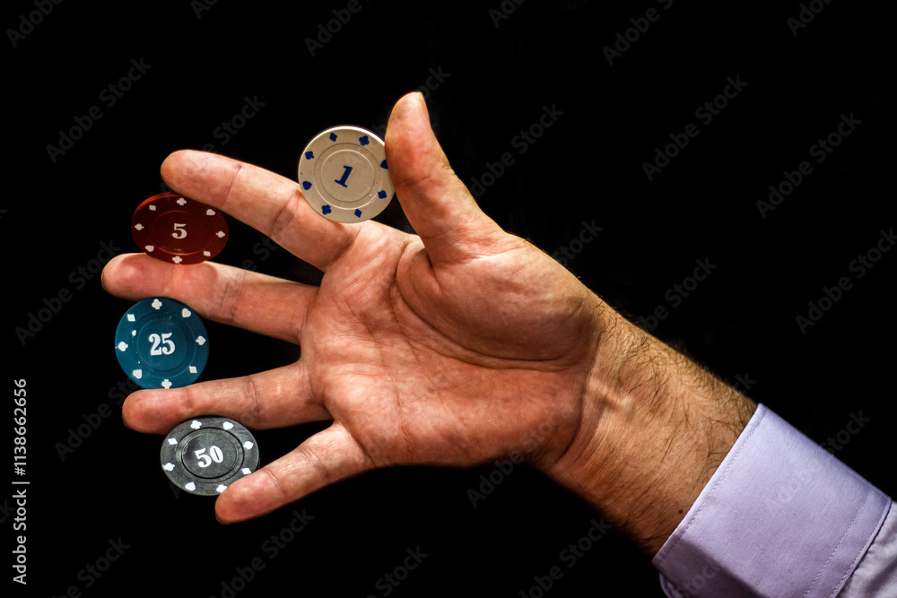 Poker chips with numbers of different colors between fingers of male ...