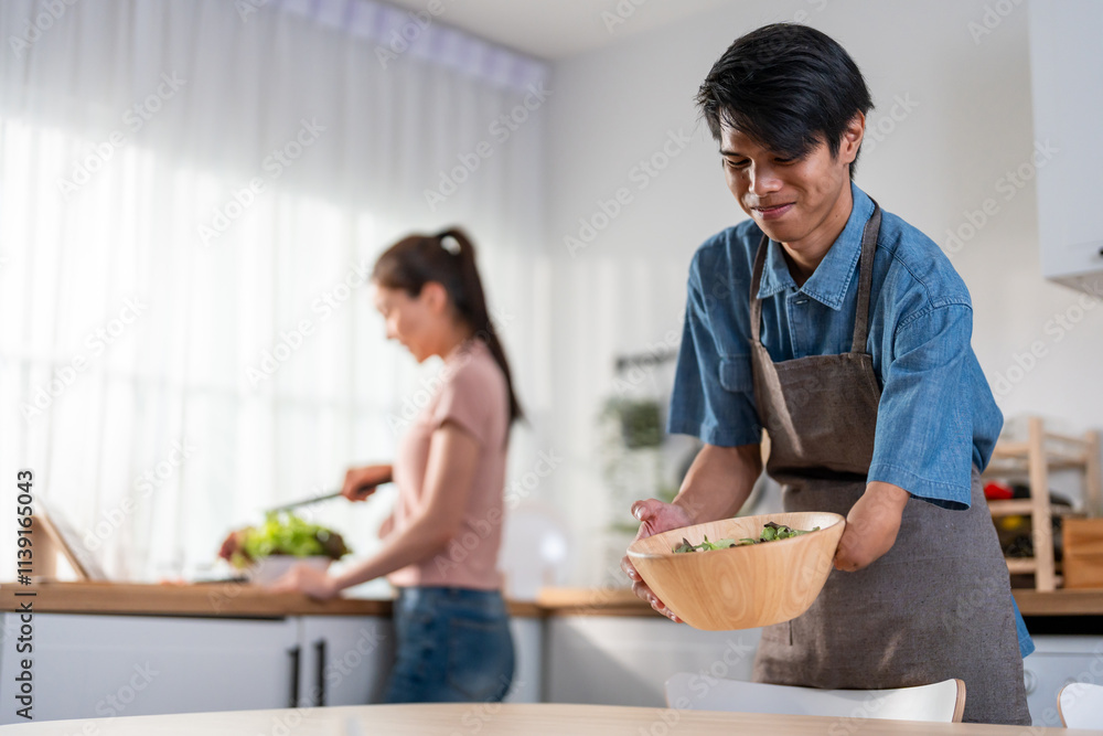 Asian young amputee without arm cooking foods with family in kitchen ...