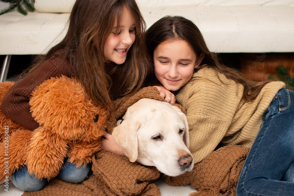 Labrador lying down and two little girls hugging the dog for Christmas ...